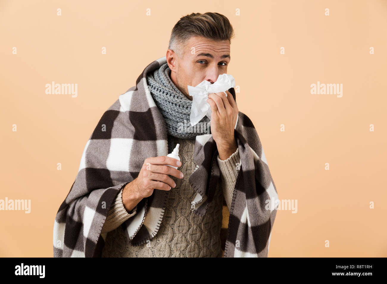 Portrait of a sick man wrapped in a blanket standing isolated over ...
