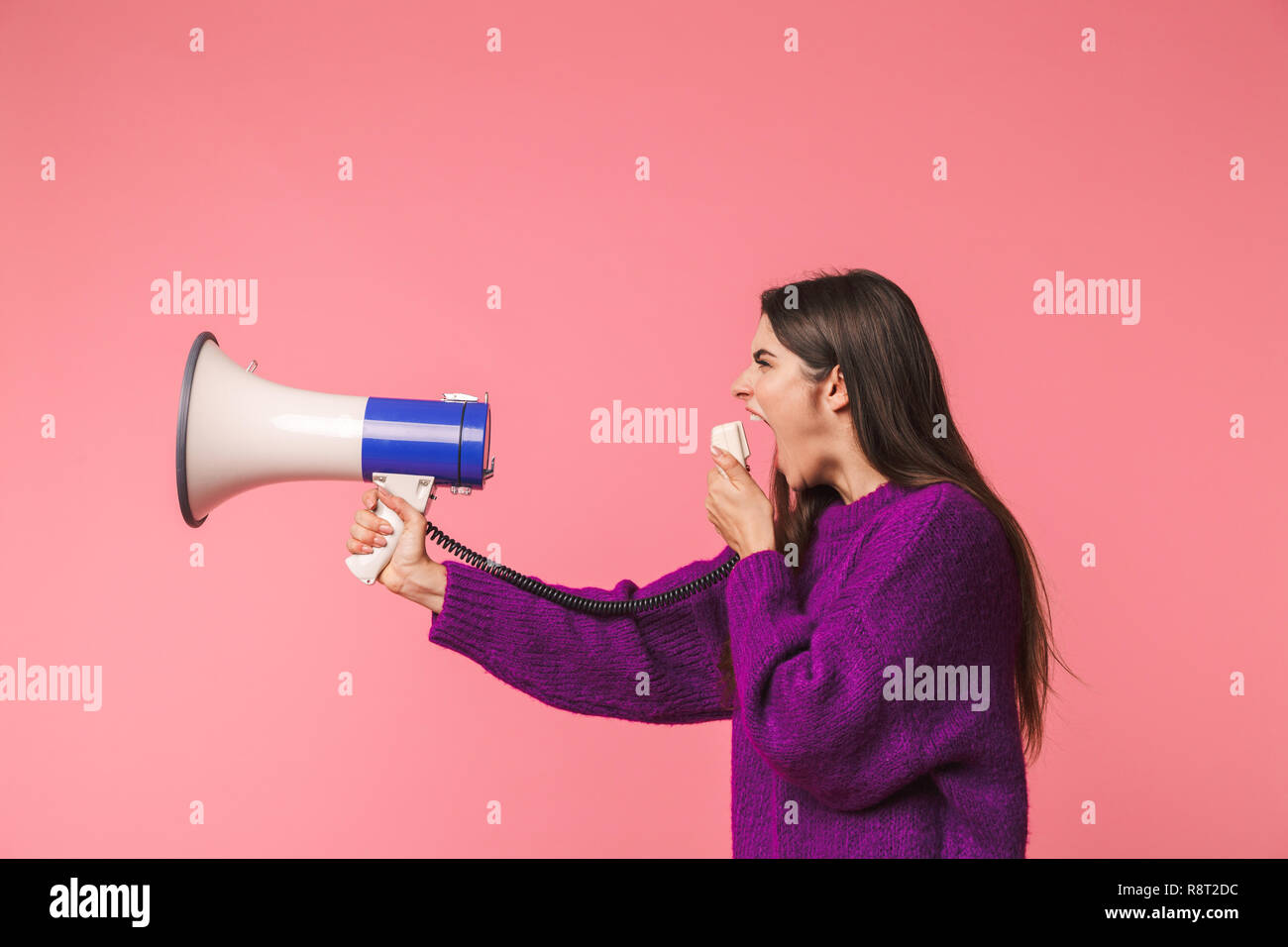 Angry young girl wearing sweater standing isolated over pink background ...