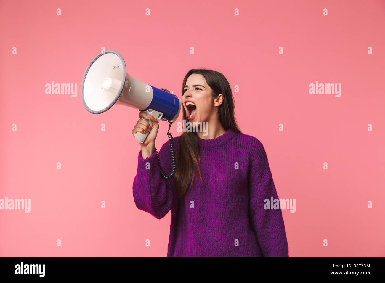 Angry young girl wearing sweater standing isolated over pink background ...