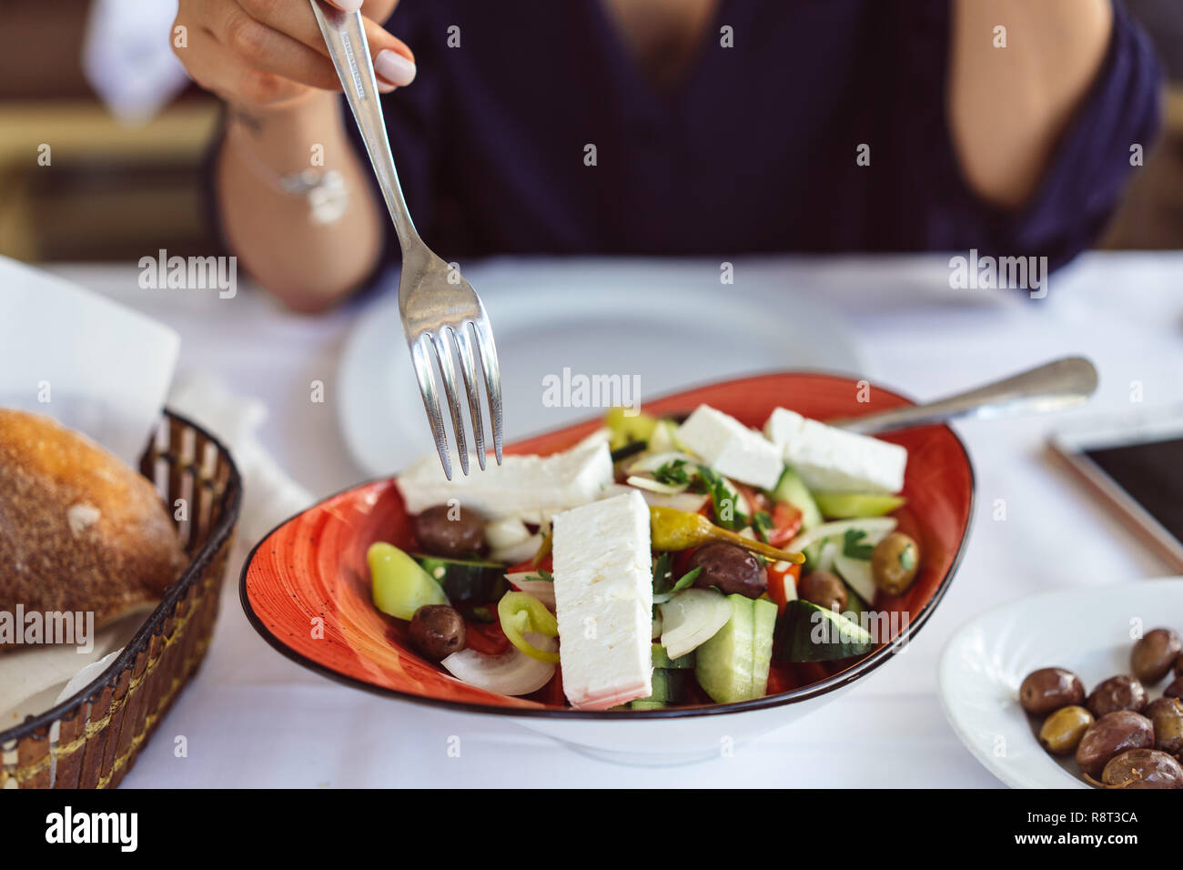 Greek salad, female hands hold a fork Stock Photo - Alamy