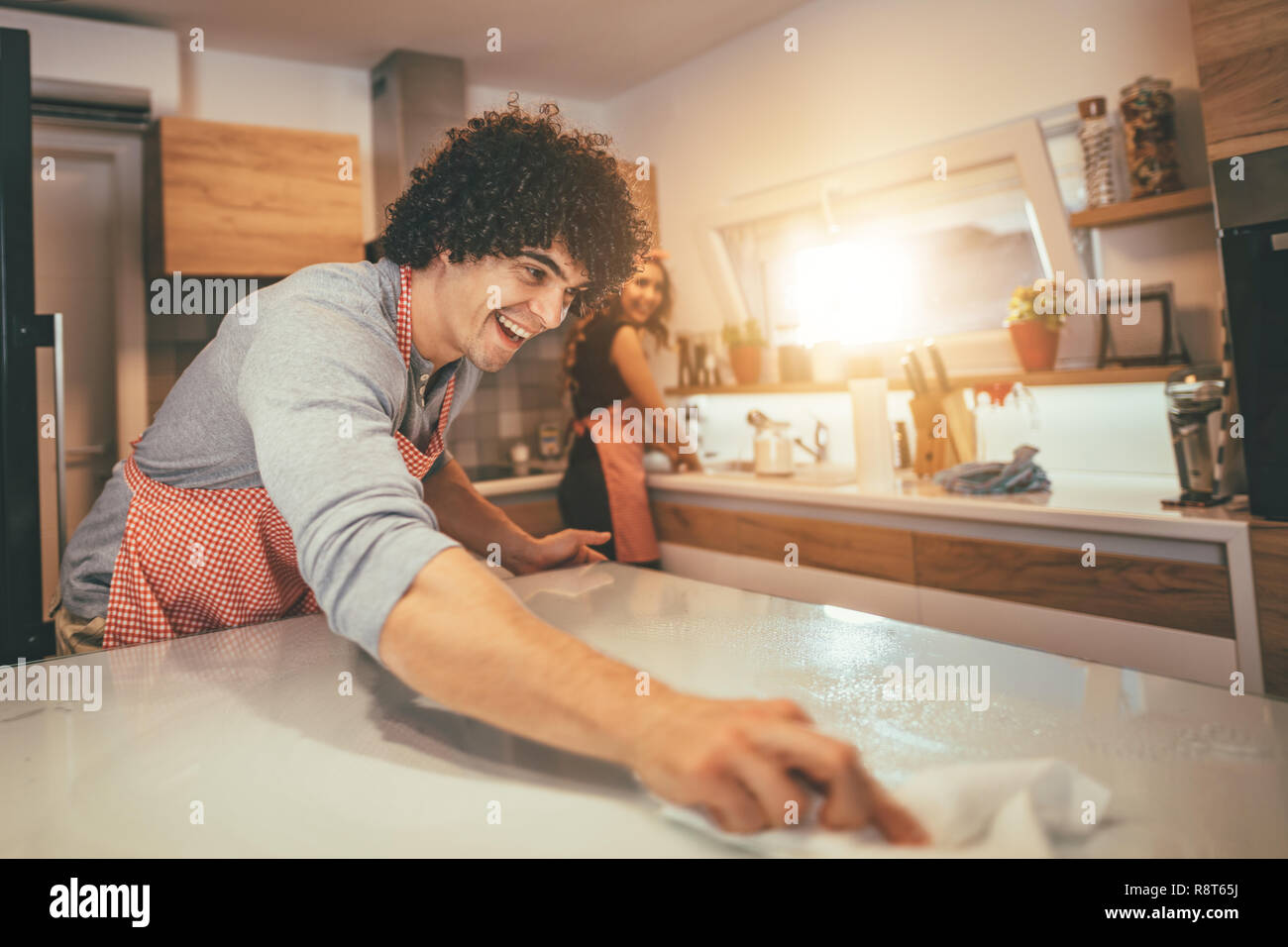 Young couple is prepared dinner, and a man is cleaning the table after ...