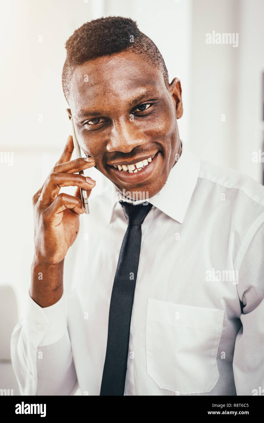 A portrait of a satisfied African businessman who is talking on ...