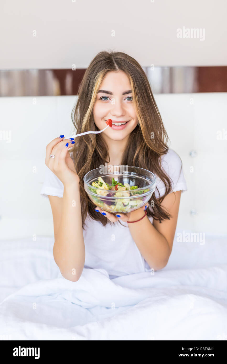 gorgeous young woman lying on bed eating vegetable salad Stock Photo ...