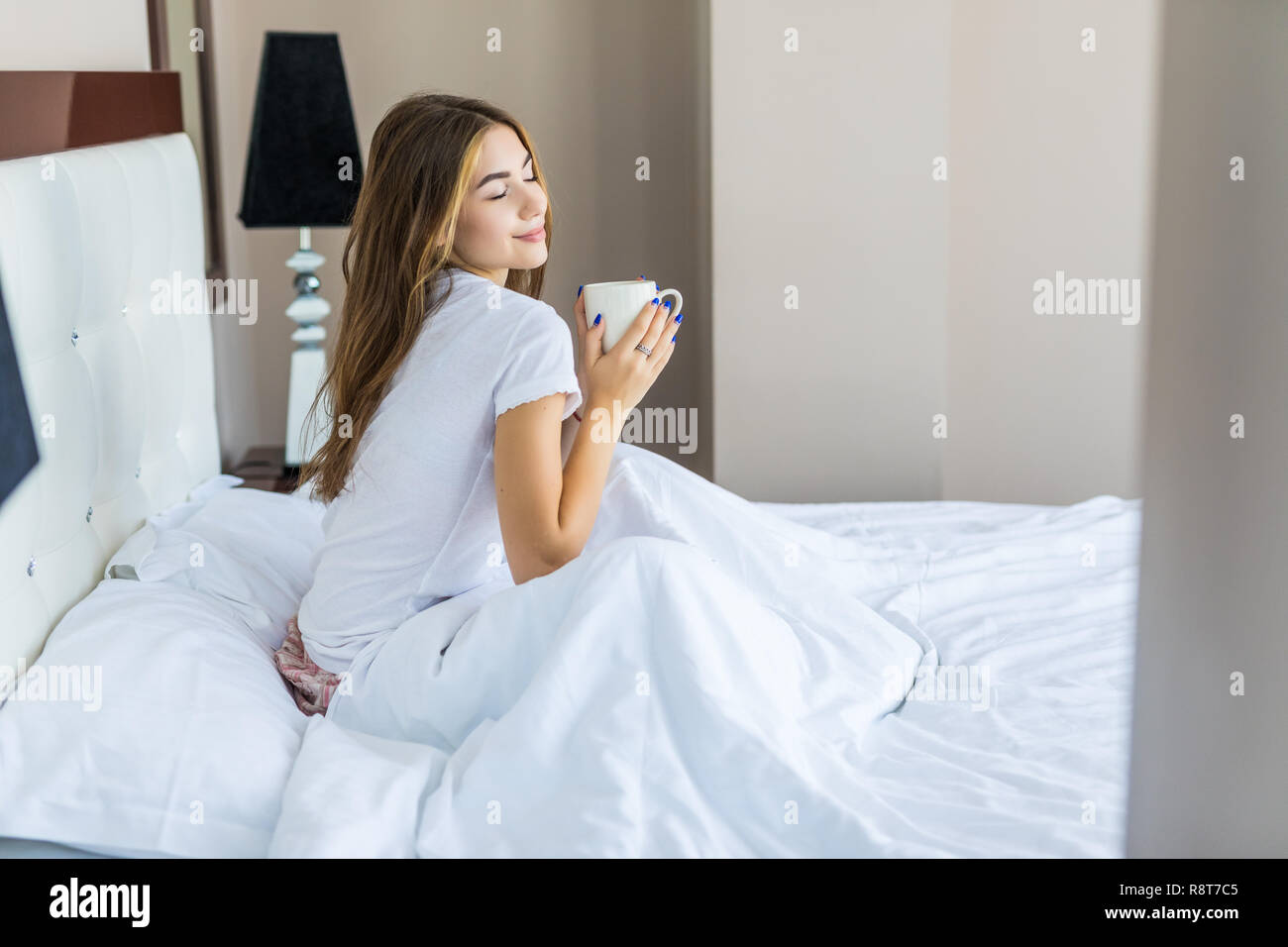 Young woman in bed with mug of something hot Stock Photo - Alamy