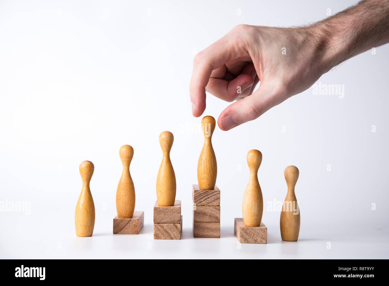 Hand selecting a wooden figure. Business leadership concept Stock Photo ...