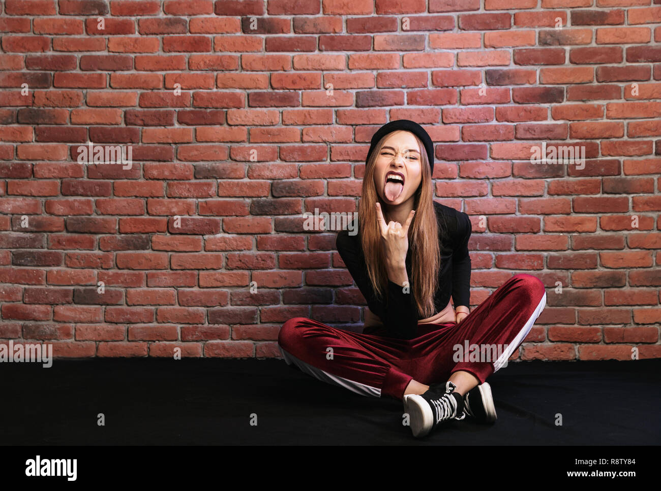 Photo of stylish hip hop dancer or sporty girl sitting on floor against ...