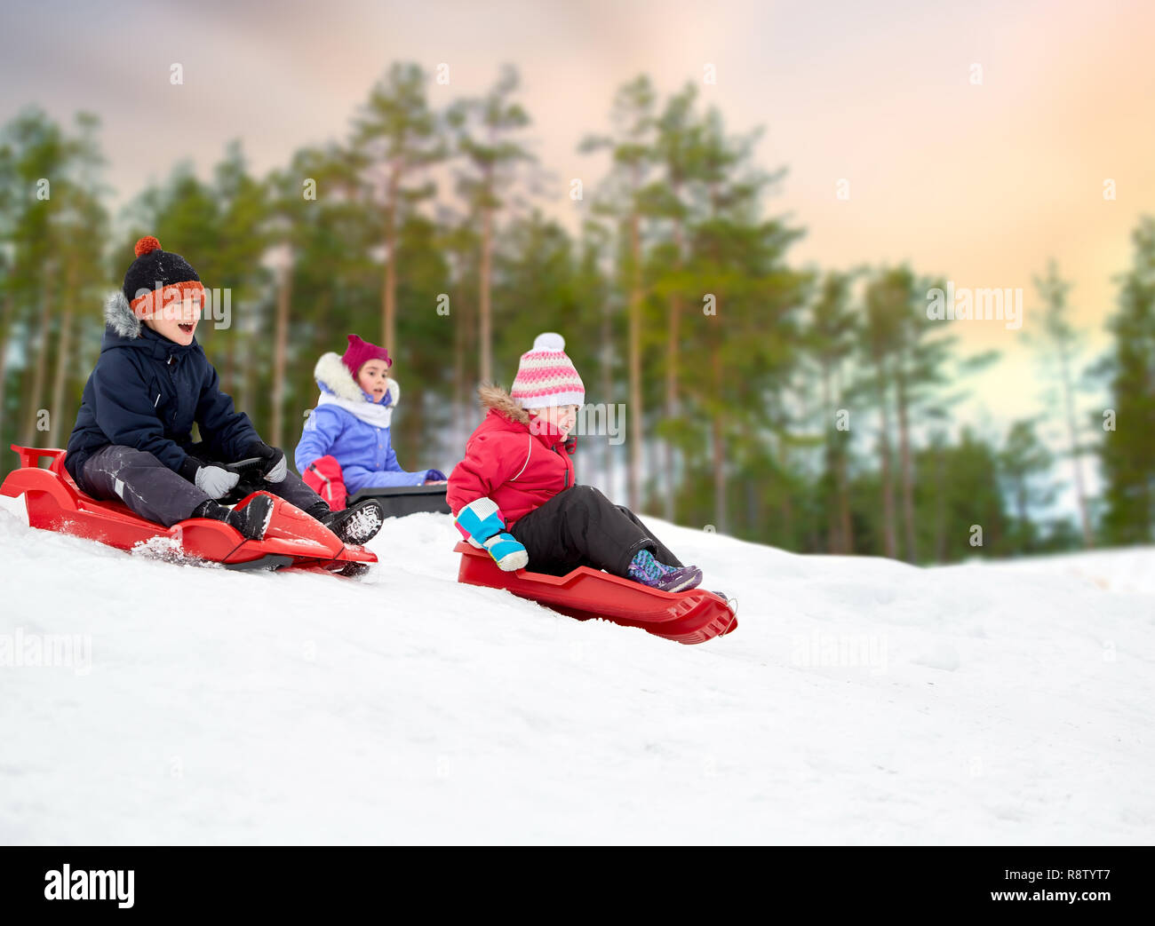 kids sliding on sleds down snow hill in winter Stock Photo - Alamy