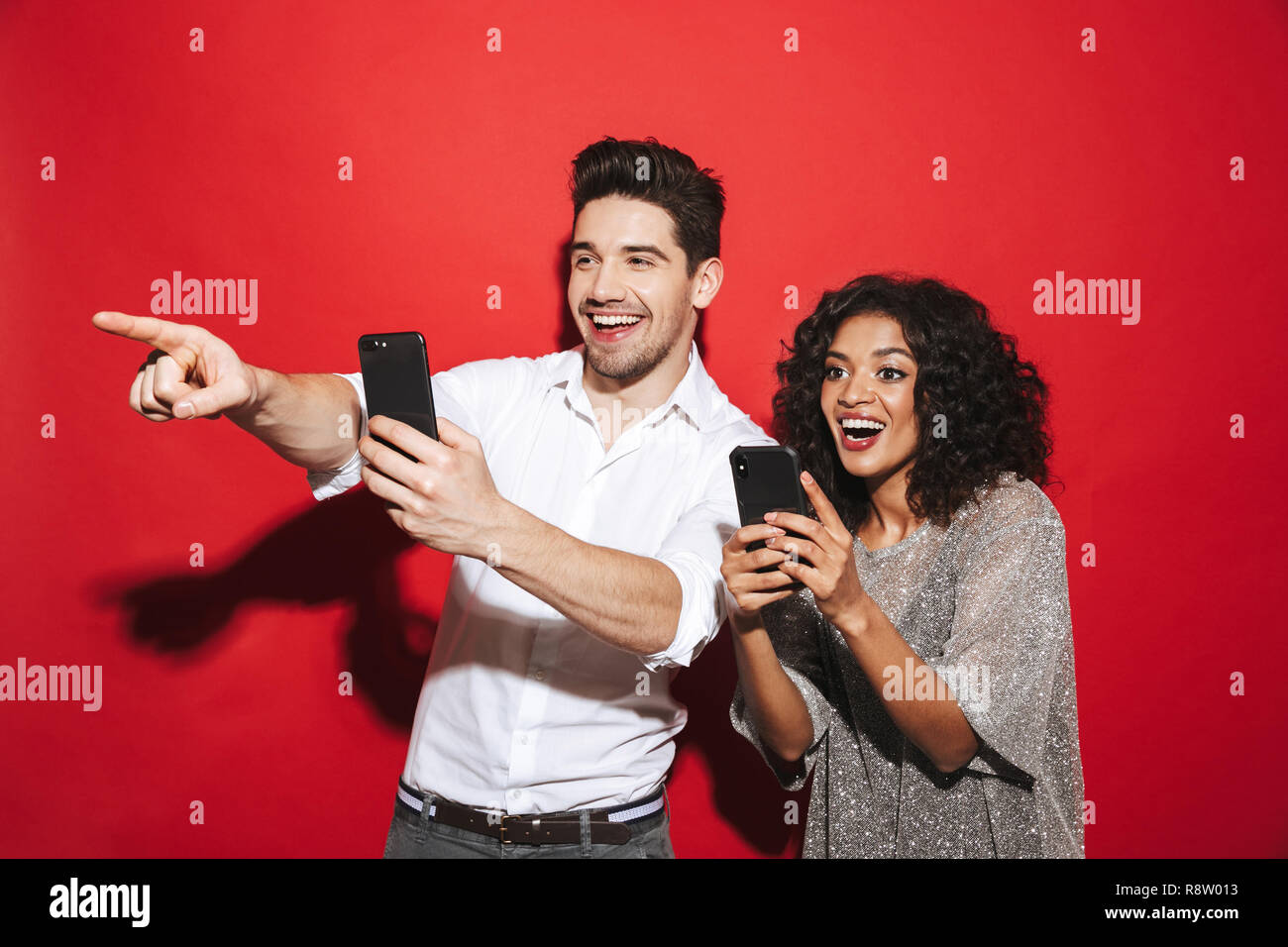 Portrait of a cheerful young smartly dressed couple standing isolated ...
