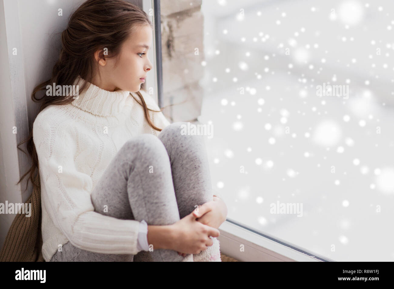 sad girl sitting on sill at home window in winter Stock Photo - Alamy
