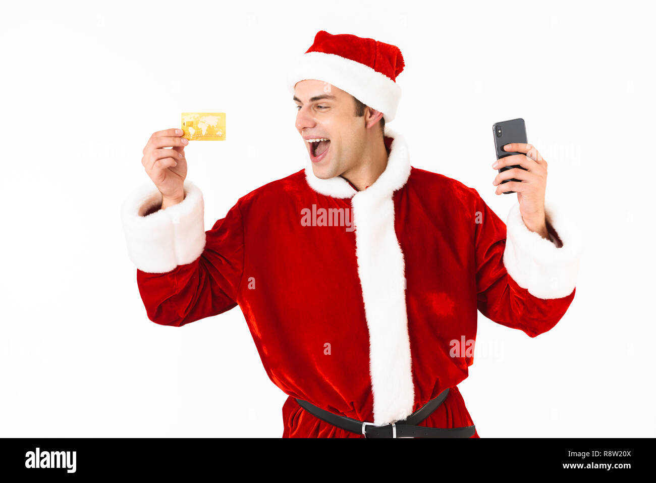 Image of optimistic man 30s in santa claus costume holding cell phone ...