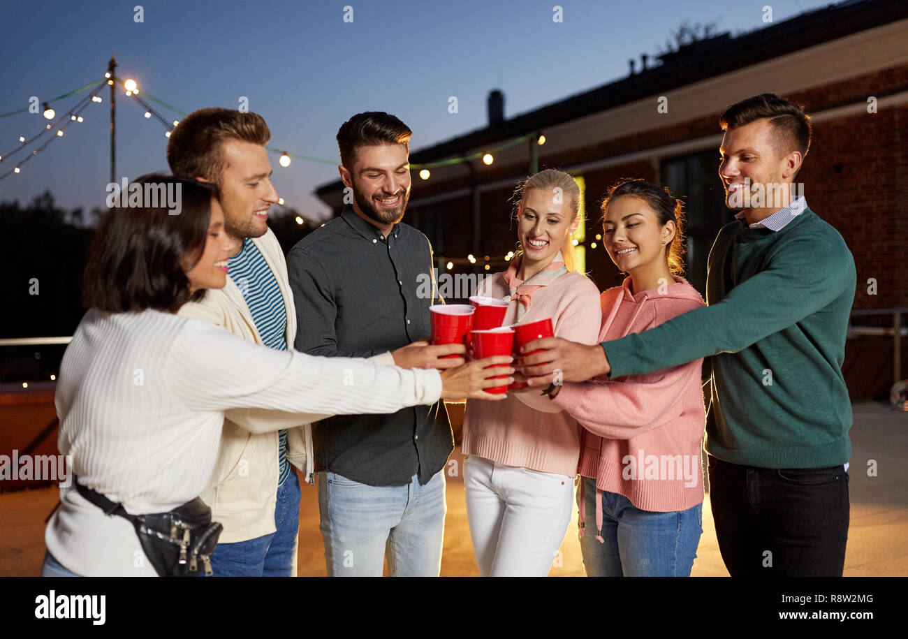 friends clinking party cups on rooftop at night Stock Photo - Alamy