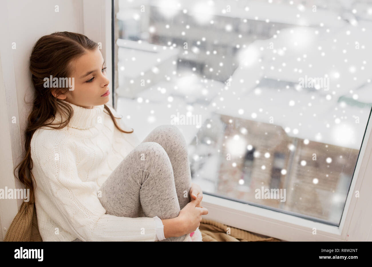sad girl sitting on sill at home window in winter Stock Photo - Alamy