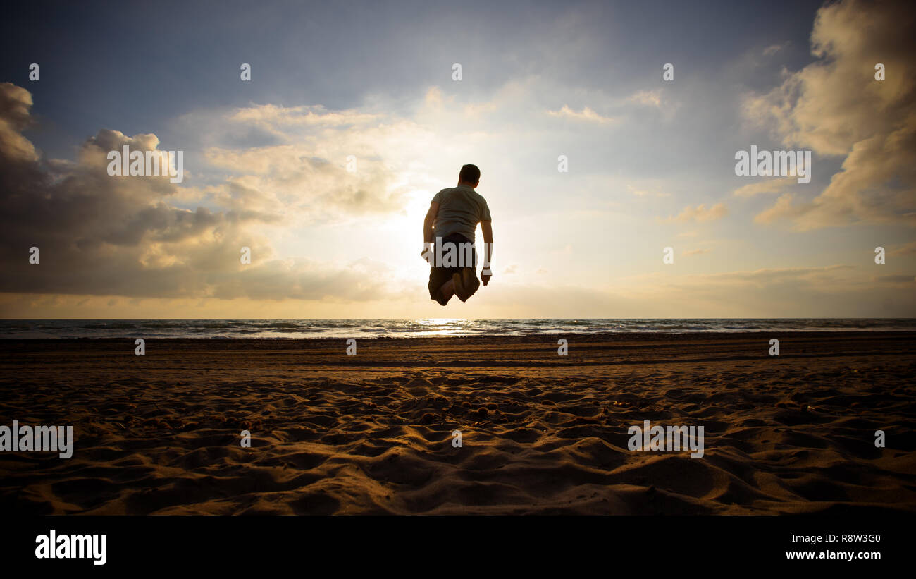 Man jumps at sunset on the beach Stock Photo - Alamy