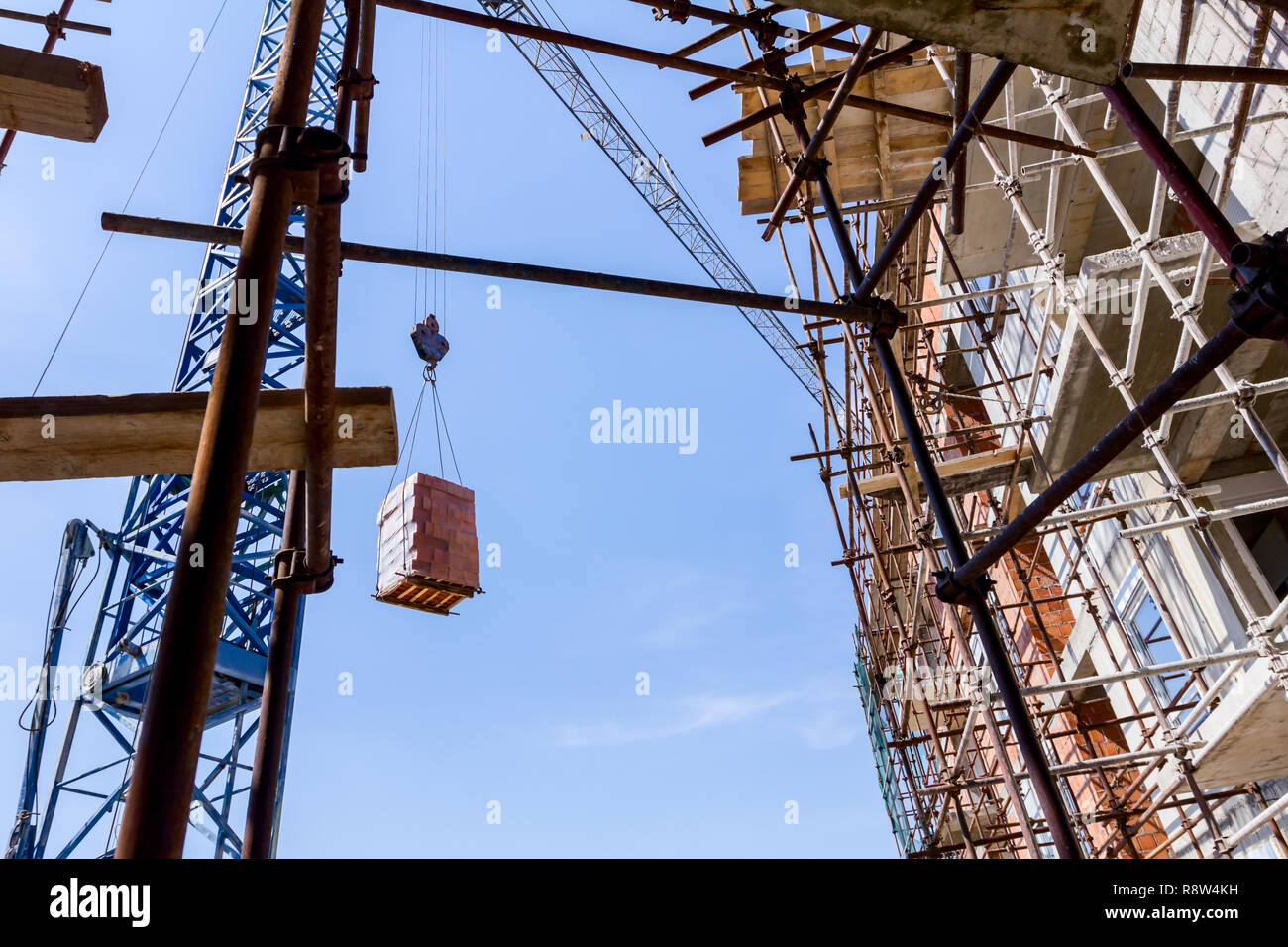 Crane is transport pack of red blocks over building site, raise up for ...