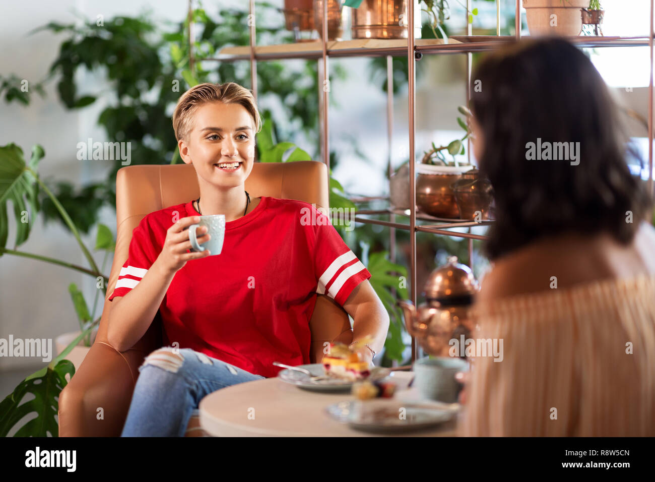 female friends drinking coffee and talking at cafe Stock Photo - Alamy