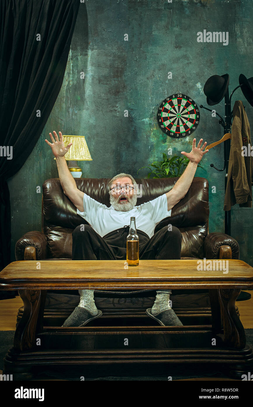 The crazy surprised football fan watching soccer game on television on ...