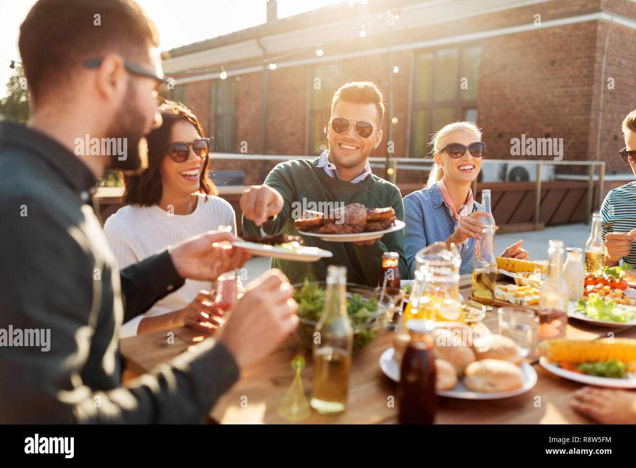 happy friends eating at barbecue party on rooftop Stock Photo - Alamy