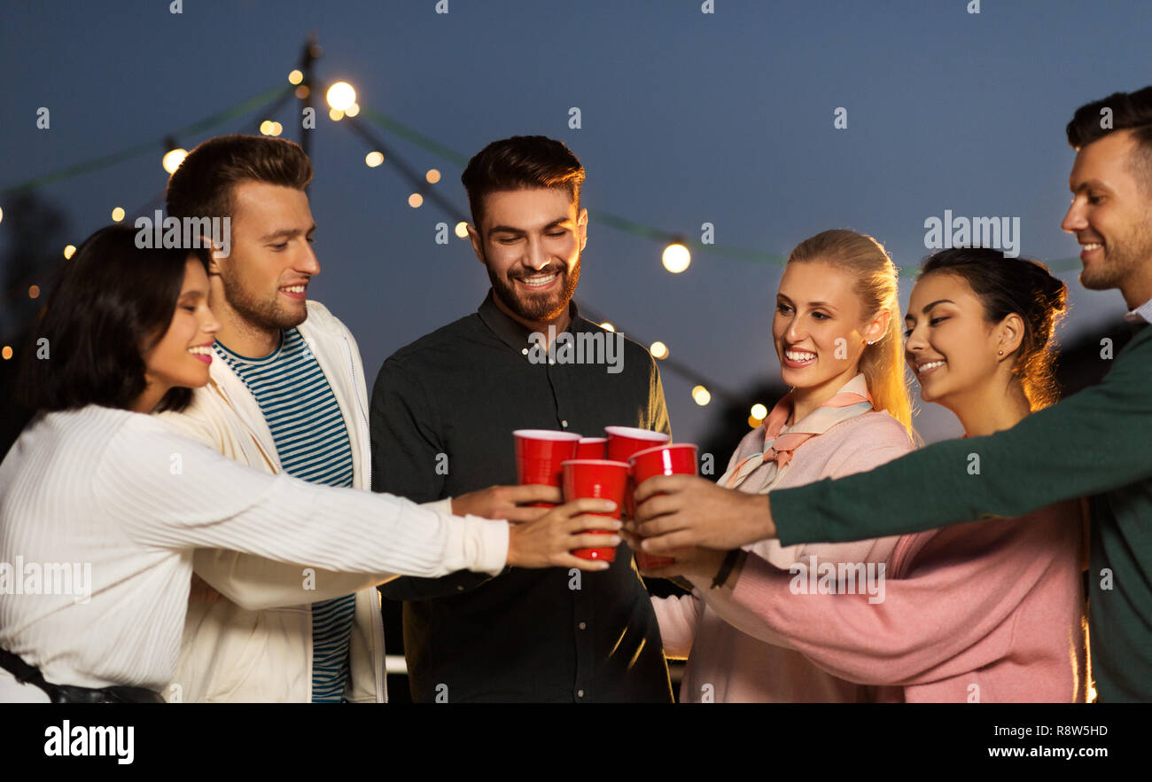 friends clinking party cups on rooftop at night Stock Photo - Alamy