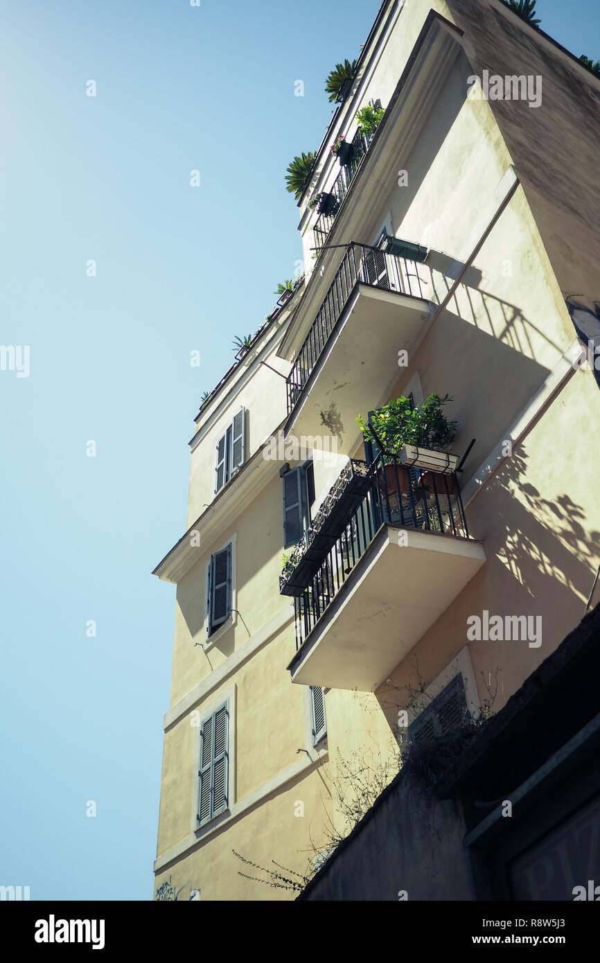 Yellow building with balconies and plants against blue sky Stock Photo ...