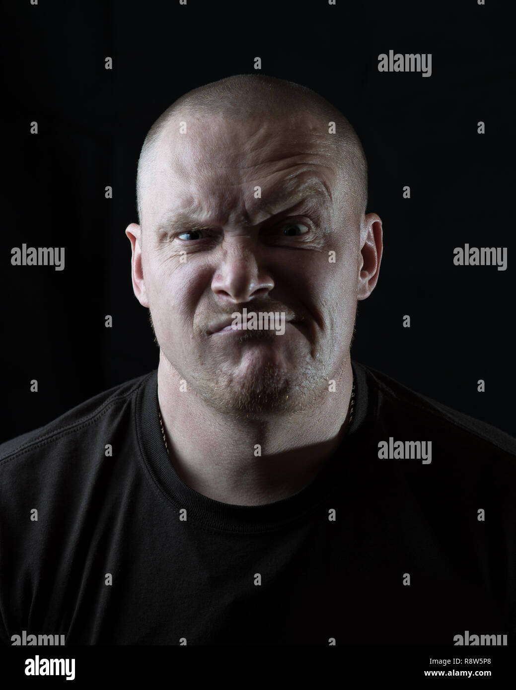 portrait of a brutal man who makes a grimace on a black background ...