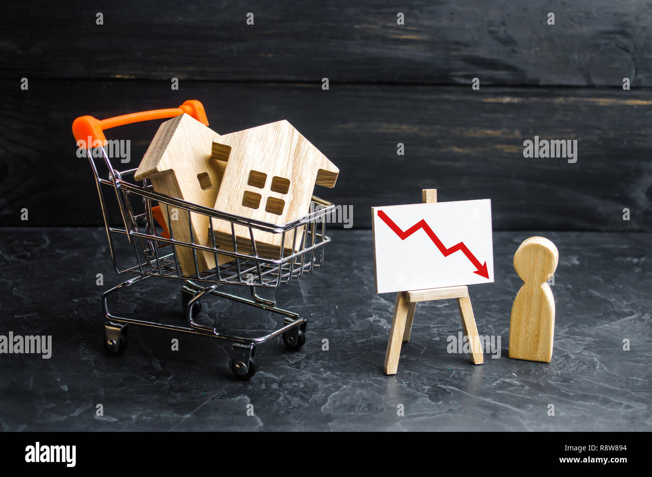 Wooden houses in a supermarket cart and up down and realtor. Reduction ...