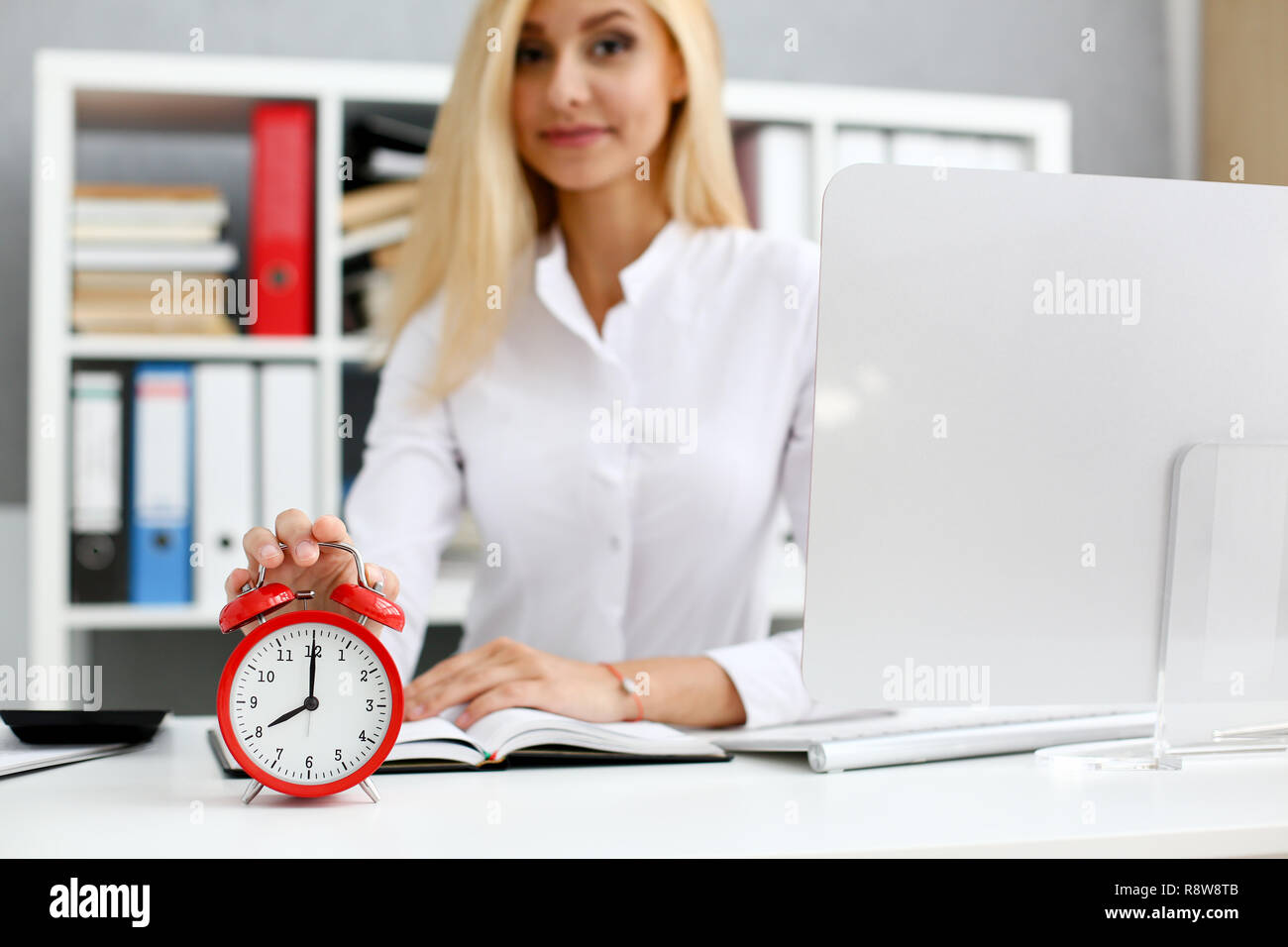 Female hand on the alarm clock a red color stands in Stock Photo - Alamy