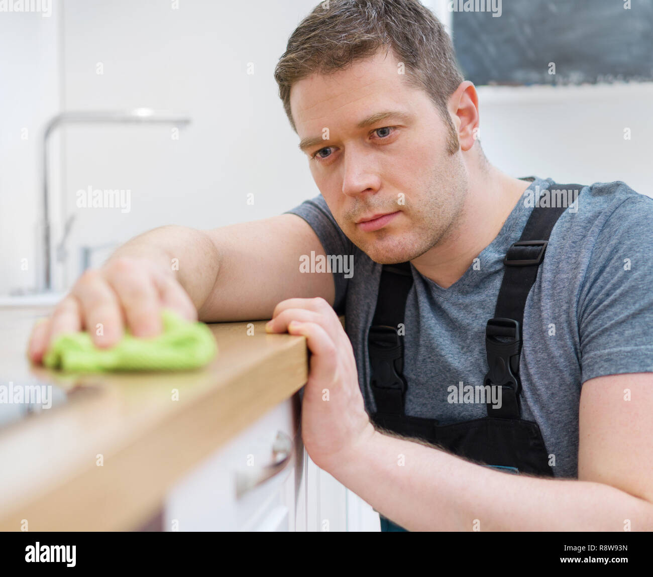 Cleaning service concept. Man cleaning kitchen furniture Stock Photo ...