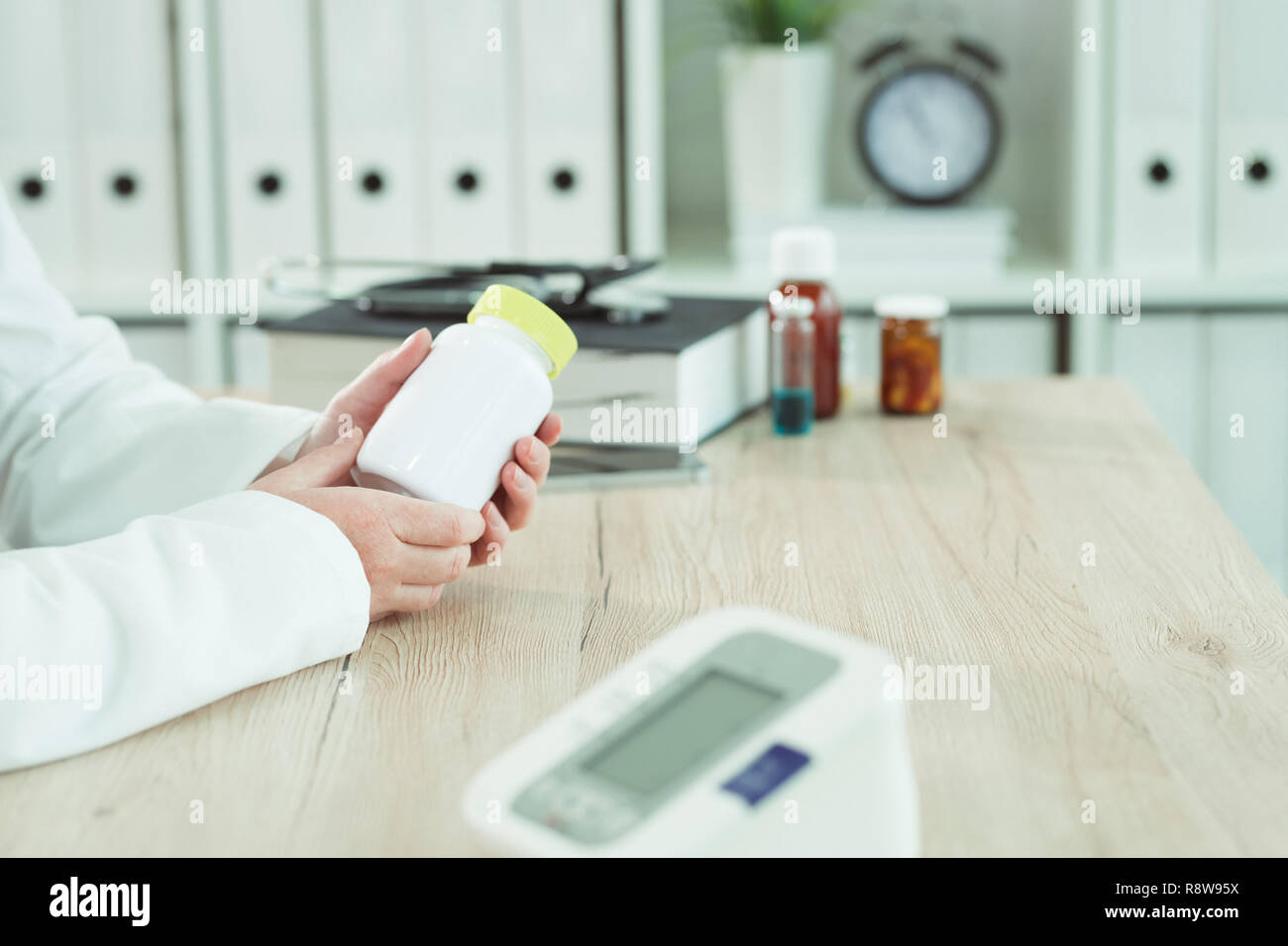 Female doctor holding bottle of dietary supplement in medical office ...