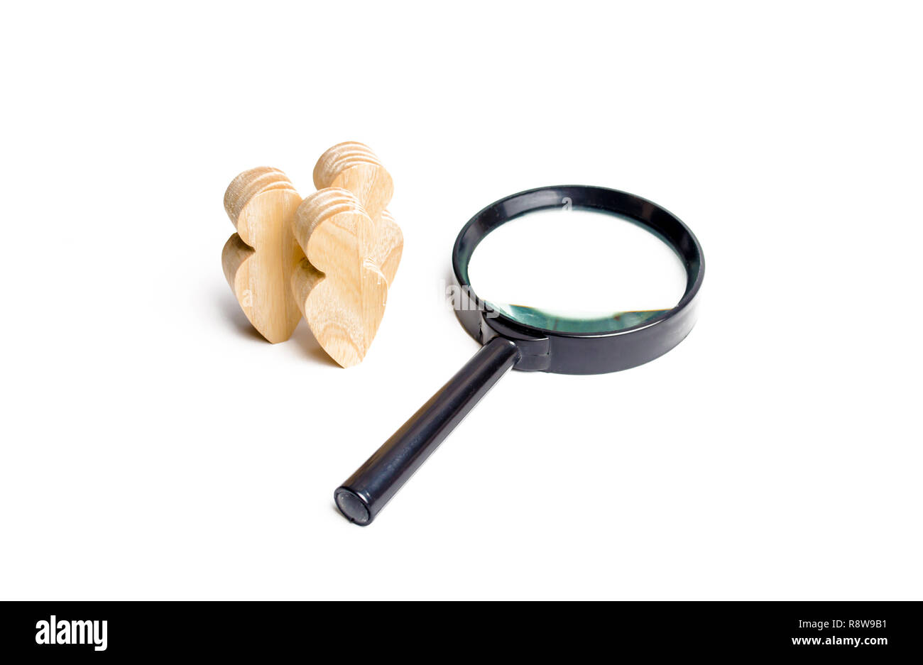Three Wooden Human Figure Stands Near A Magnifying Glass On A White
