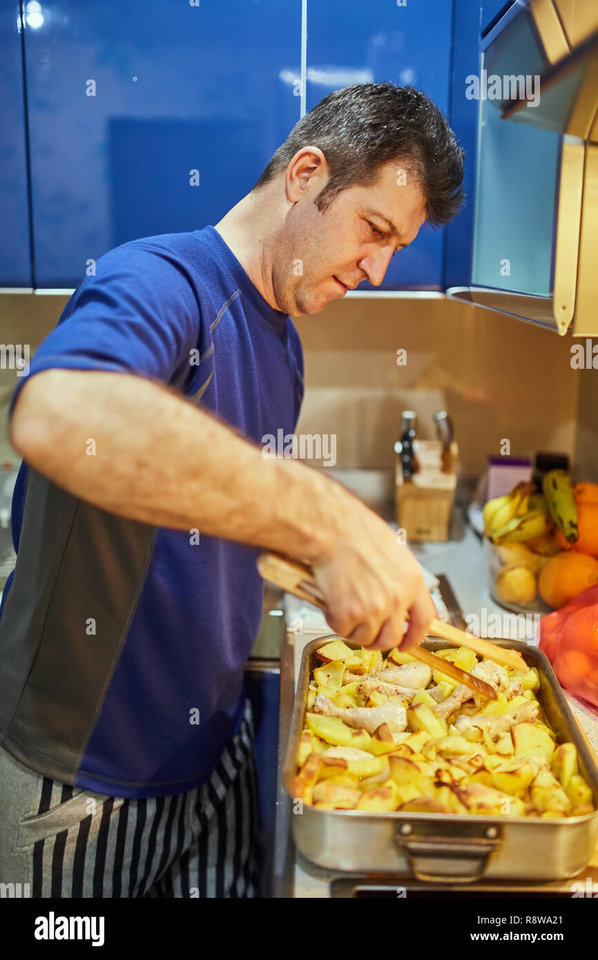 Man cooking at home a tray of chicken drumsticks and vegetables Stock ...