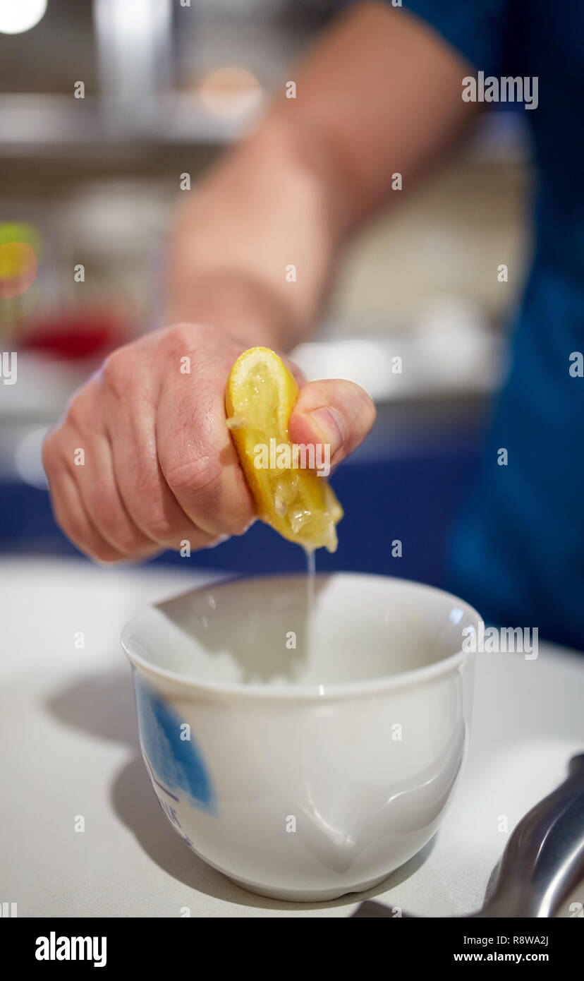 Man's hand squeezing a lemon into a cup Stock Photo - Alamy