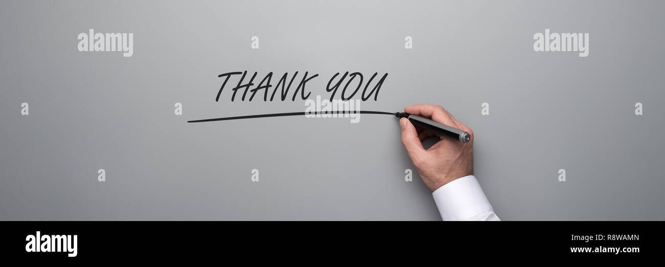 Male hand writing a Thank you note on grey backround. Wide view image ...