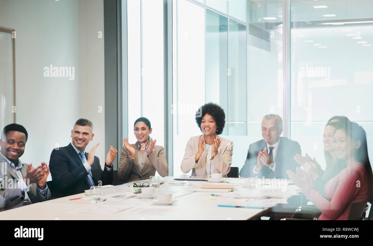 Happy, supportive business people clapping in conference room meeting ...