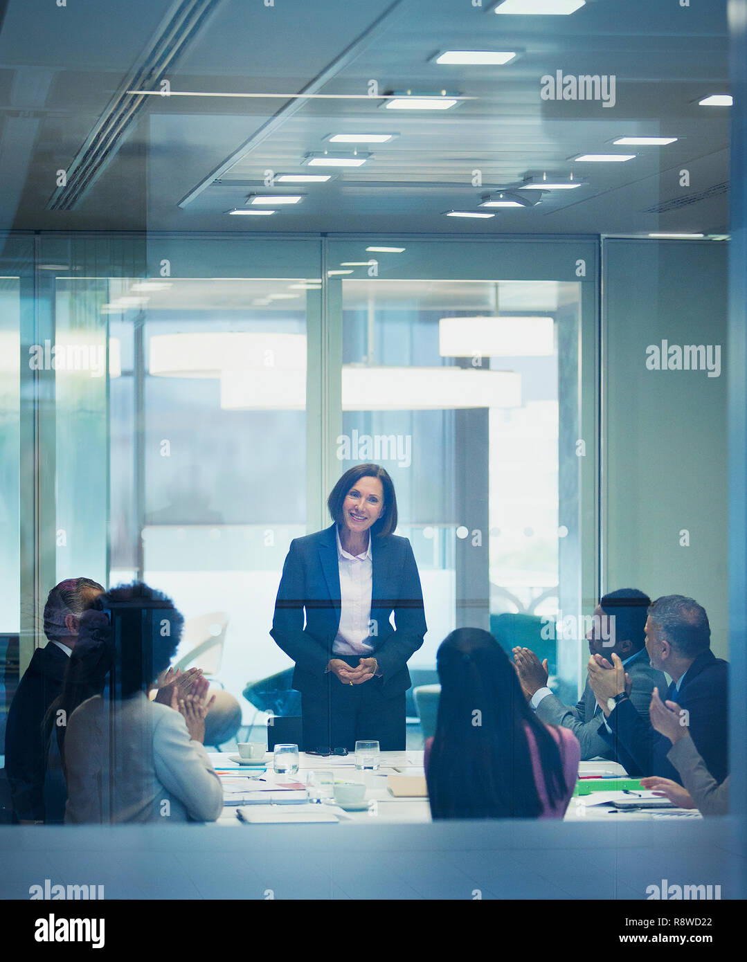 Colleagues clapping for businesswoman leading conference room meeting ...