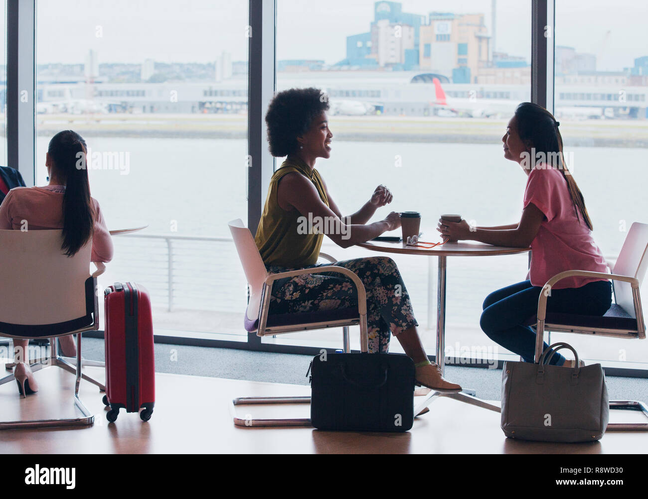 Businesswomen talking and drinking coffee in airport business lounge ...