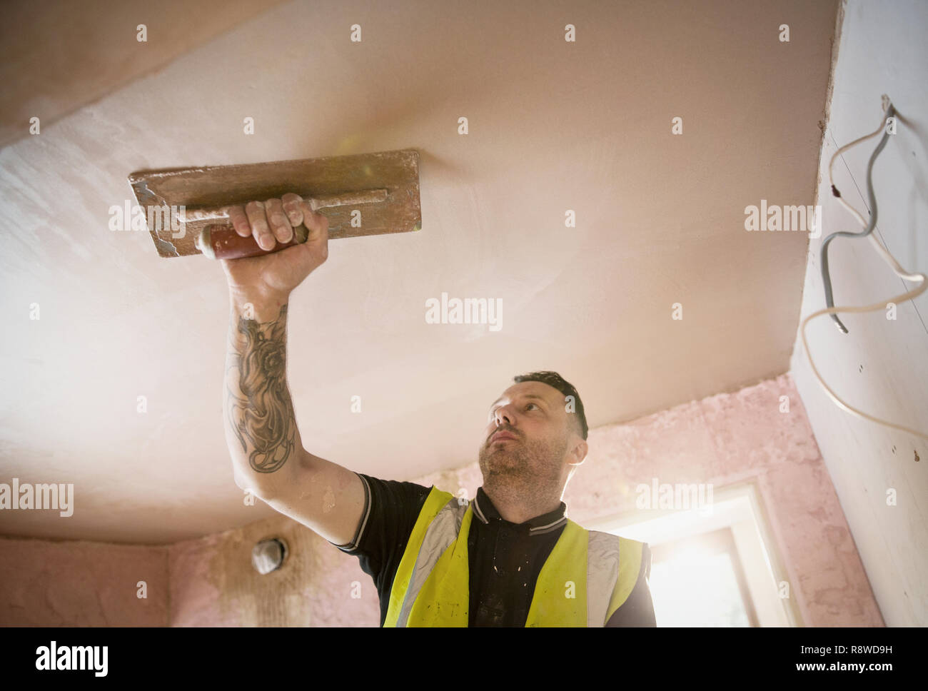 Construction worker with tattoo plastering ceiling Stock Photo - Alamy