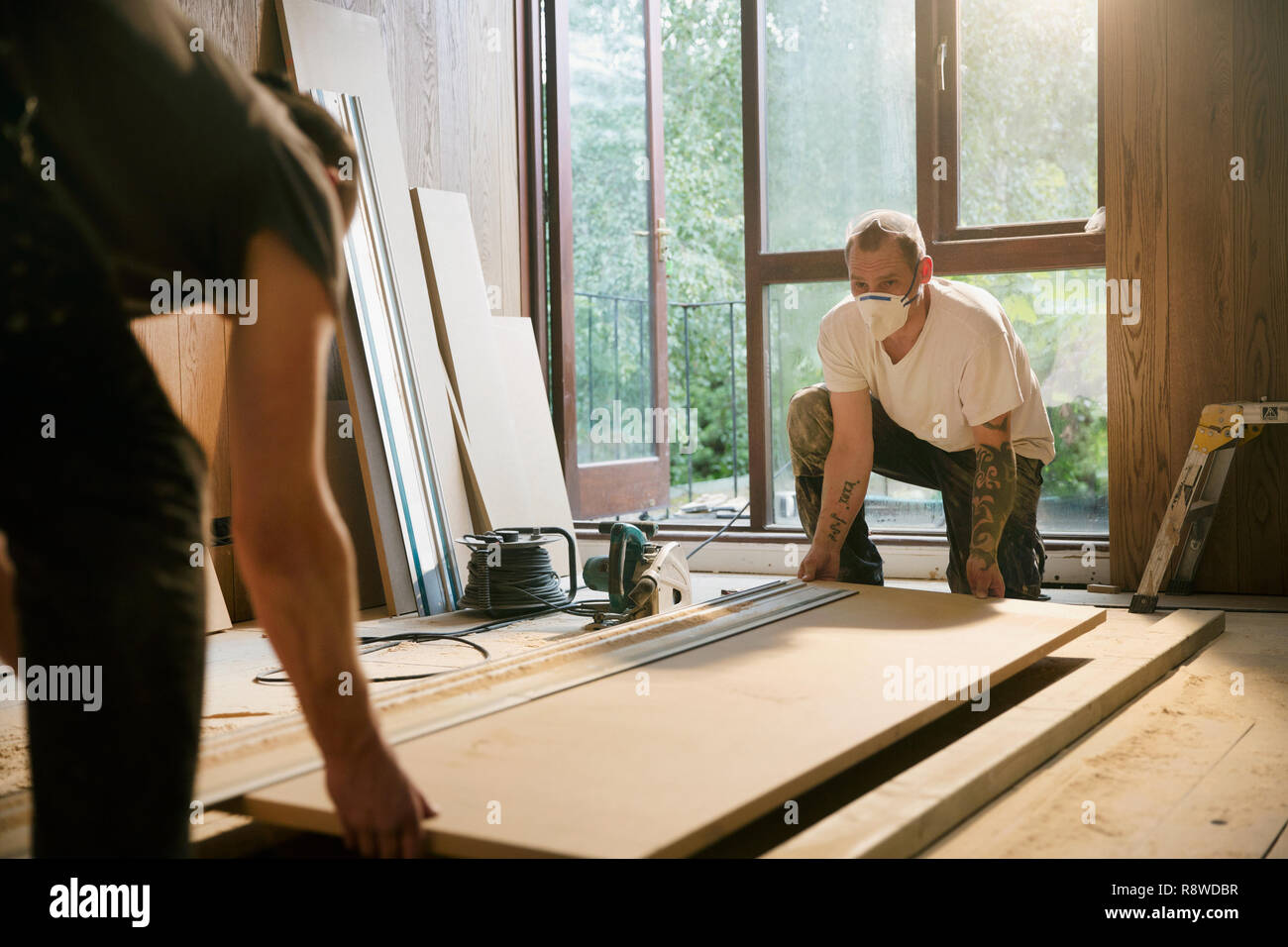Construction workers lifting wood board in house Stock Photo - Alamy