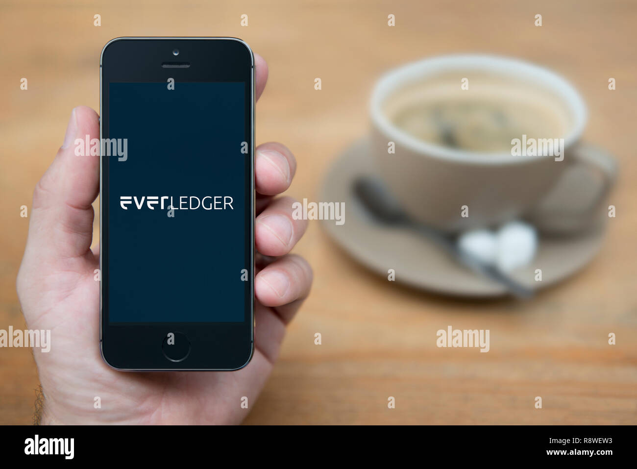 A man looks at his iPhone which displays the Everledger logo (Editorial use only Stock Photo - Alamy