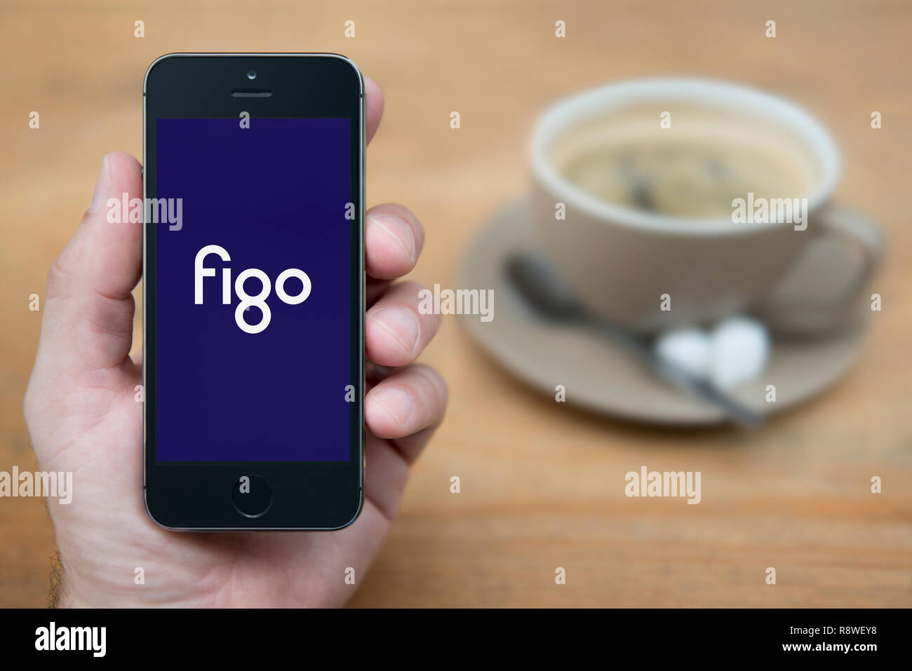A man looks at his iPhone which displays the Figo logo (Editorial use ...