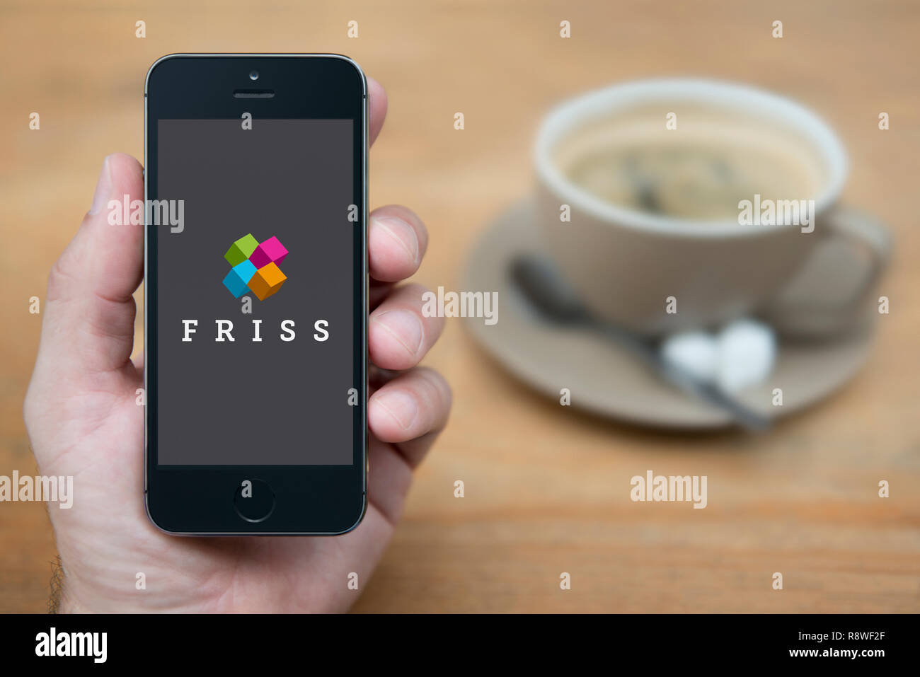 A man looks at his iPhone which displays the Friss logo (Editorial use ...