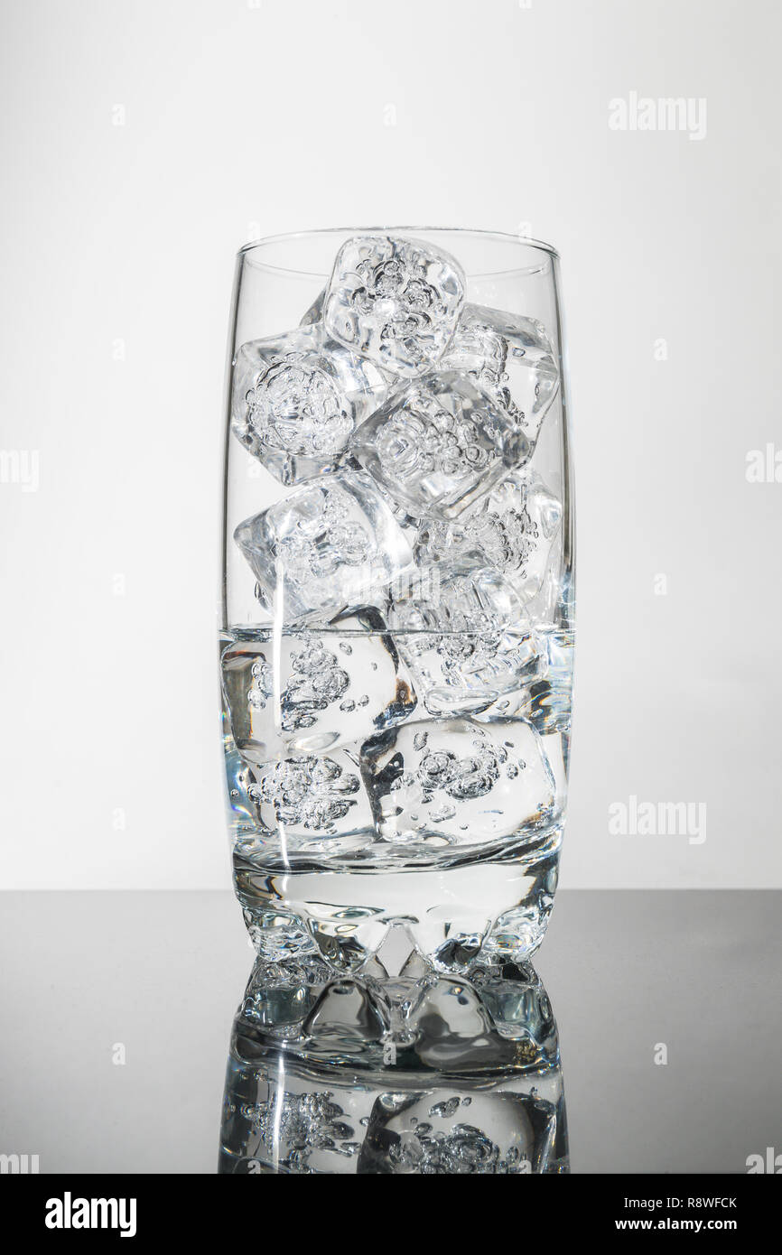ice cubes and clear liquid in glass tumbler on shiny tabletop Stock ...