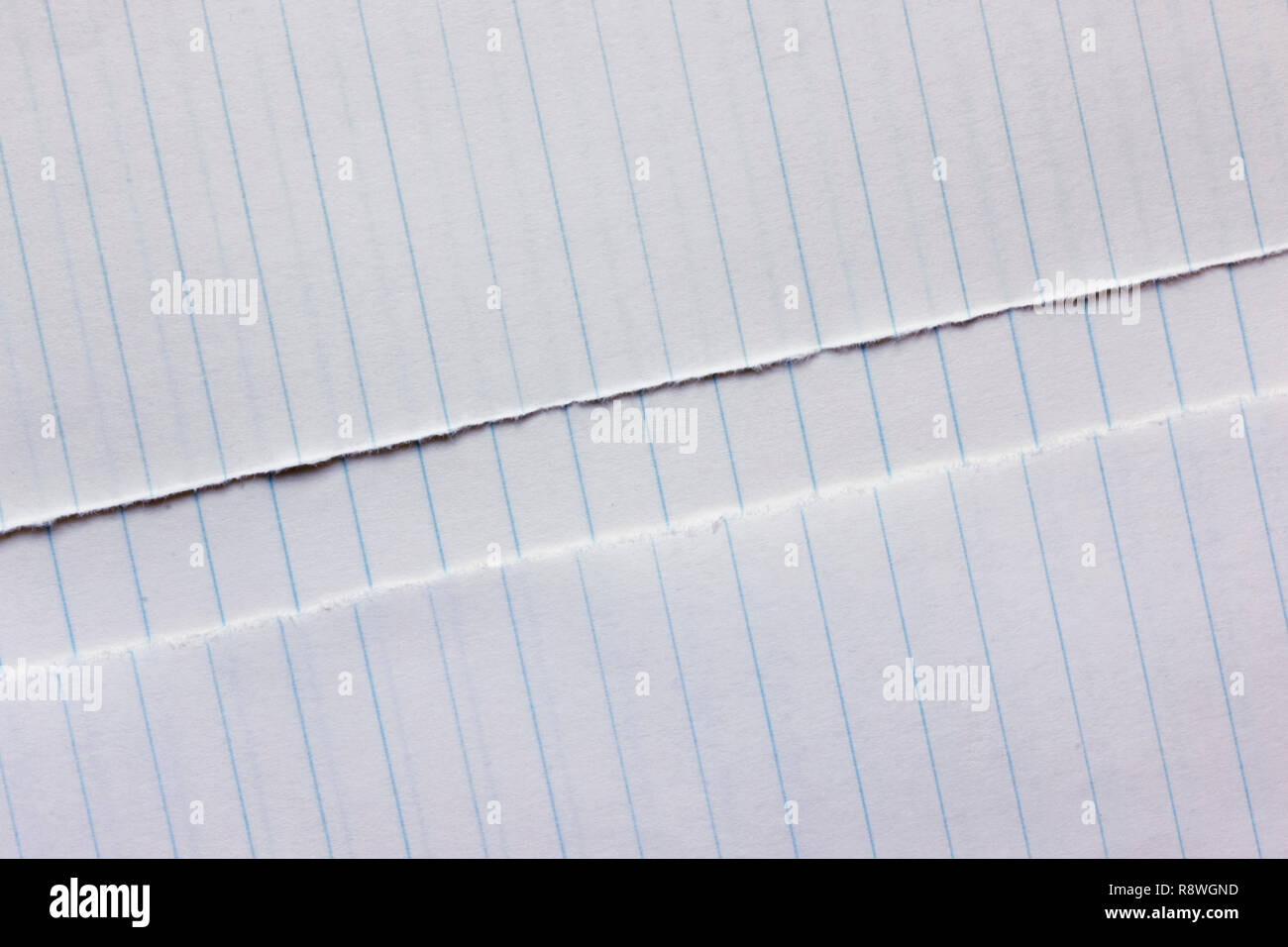 A ripped page of a lines notebook rests on the notebook itself , top ...