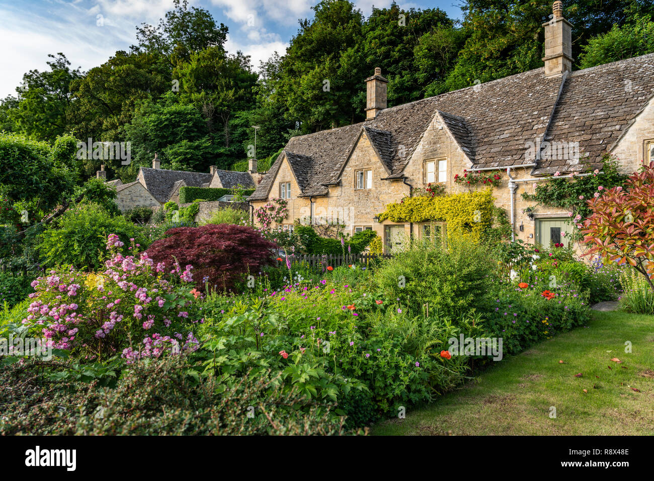 Alarge stone home with flower gardens in the Cotswold village of Bibery ...