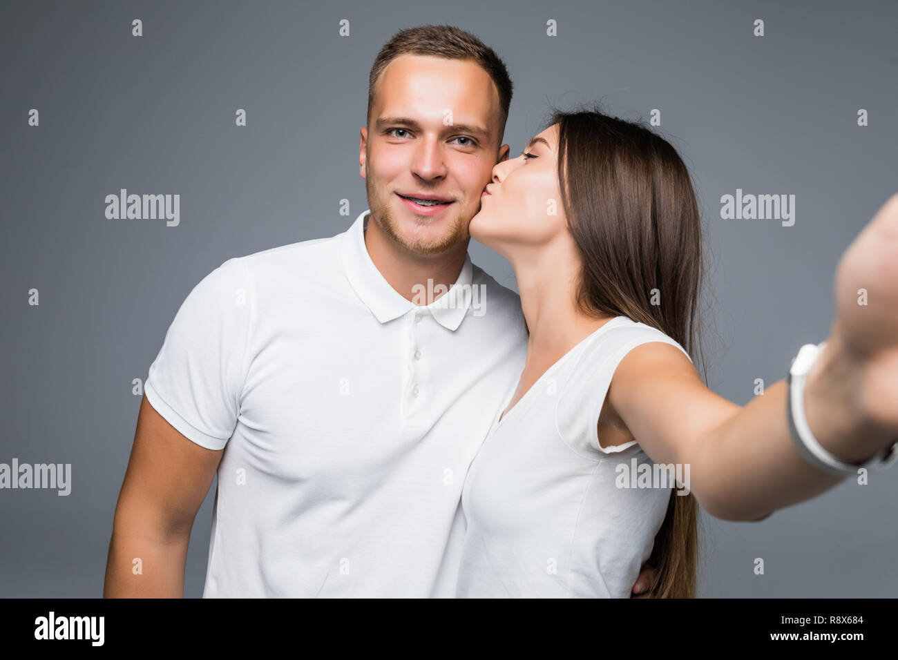 Portrait of two people making selfie while woman kissing her boyfriend ...