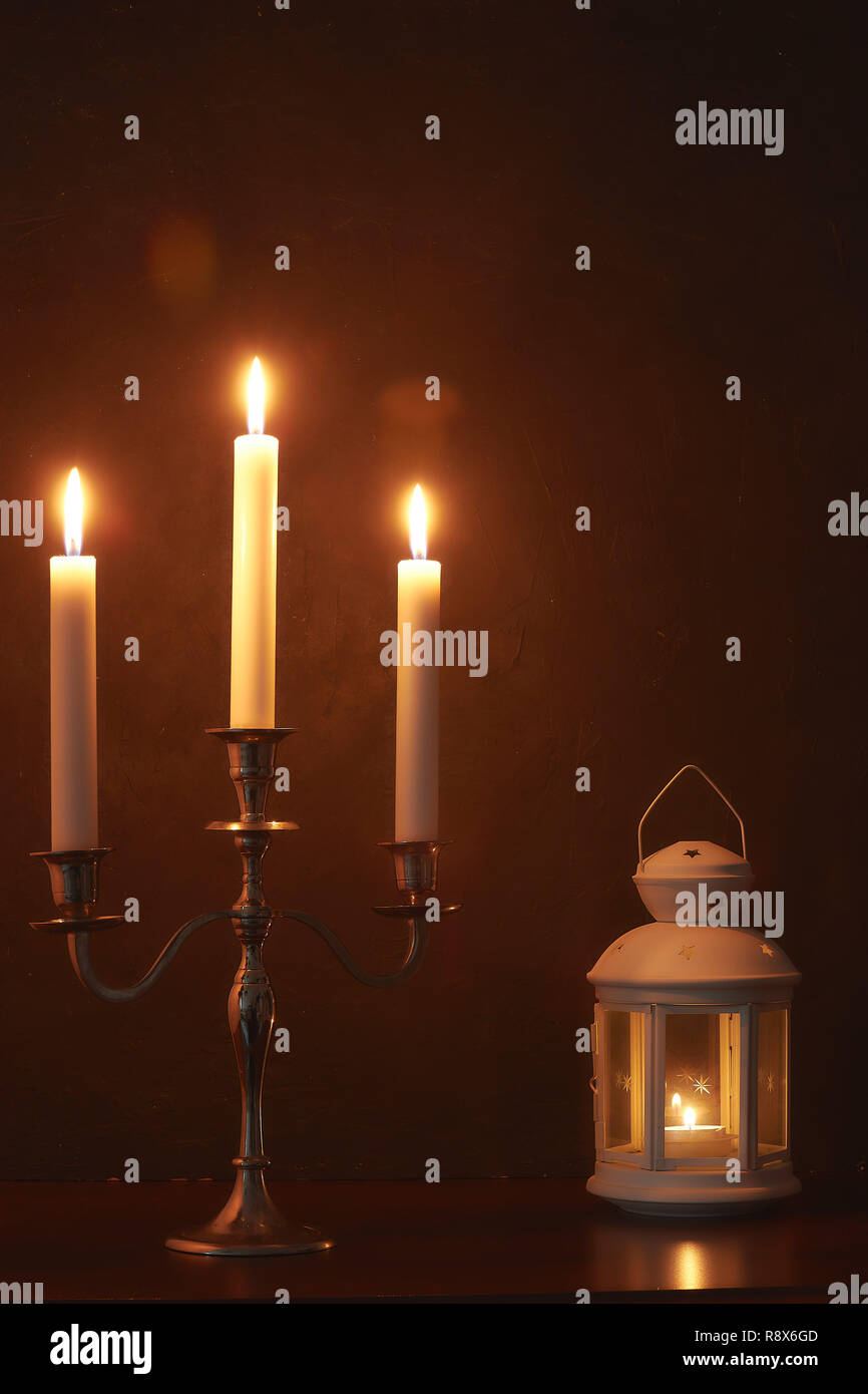 quiet home environment at night by candlelight. White candles burn in ...