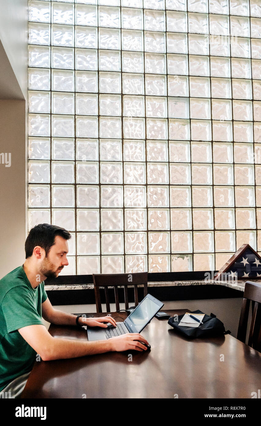 Young bearded man at home working remotely on laptop computer in front ...