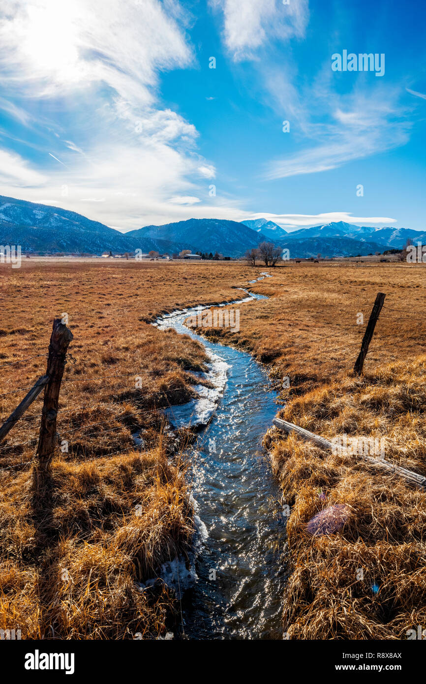 Ranch irrigation ditch & pasture; dramatic sky; Rocky Mountains ...