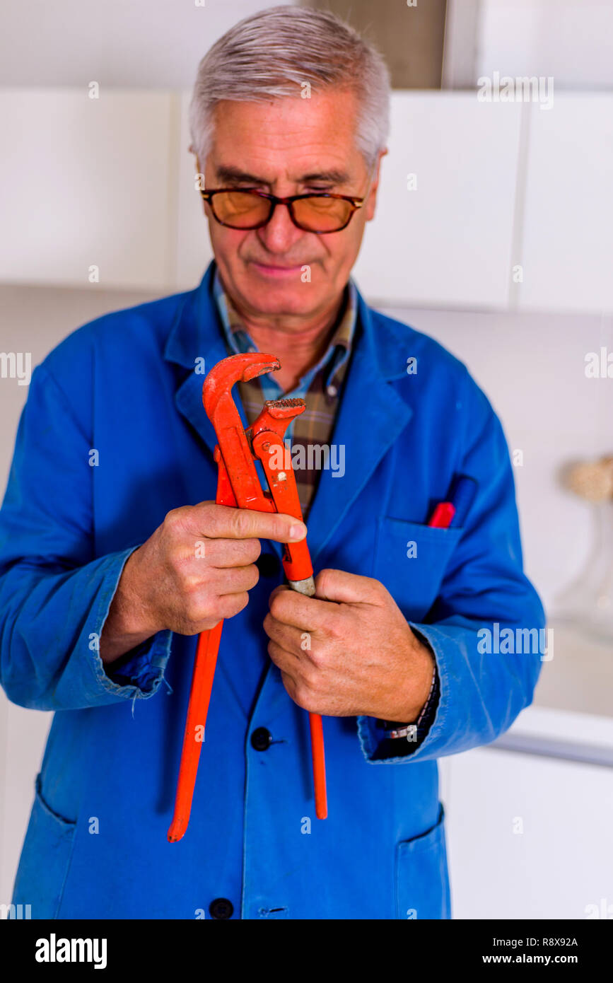 An old age handyman is standing in the kitchen with his tools Stock ...