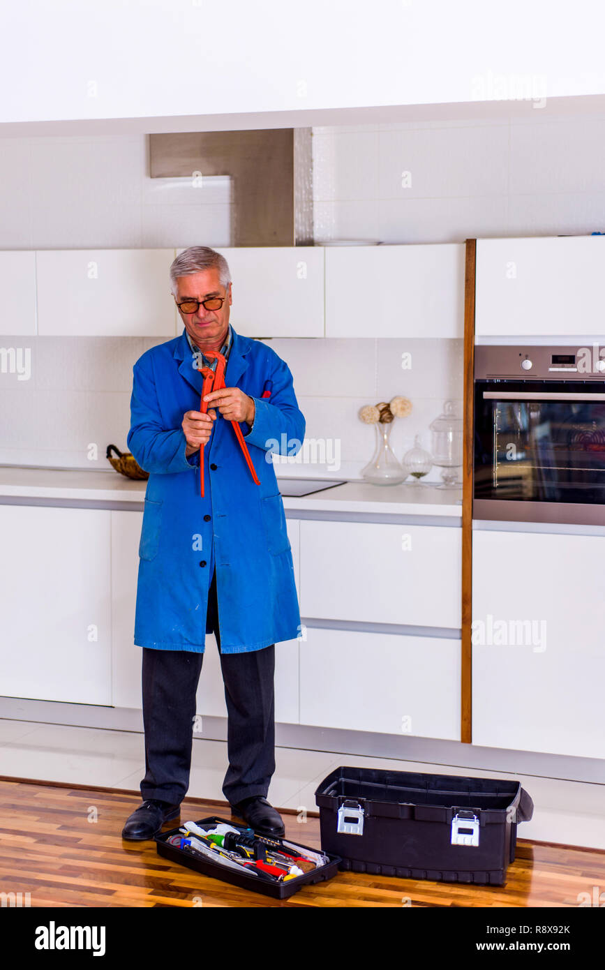 Workman standing in white kitchen with his tools and working with his ...
