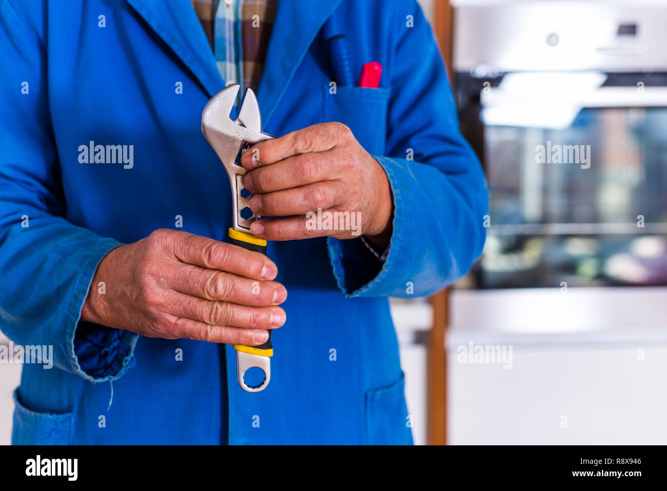 Mature male repairman is holding his tools and working in the kitchen ...